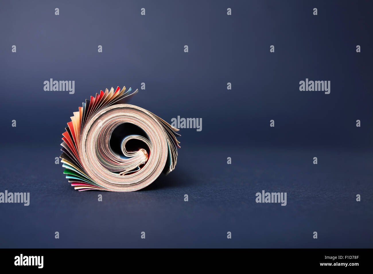 Rolled up magazine isolated on blue background Stock Photo - Alamy