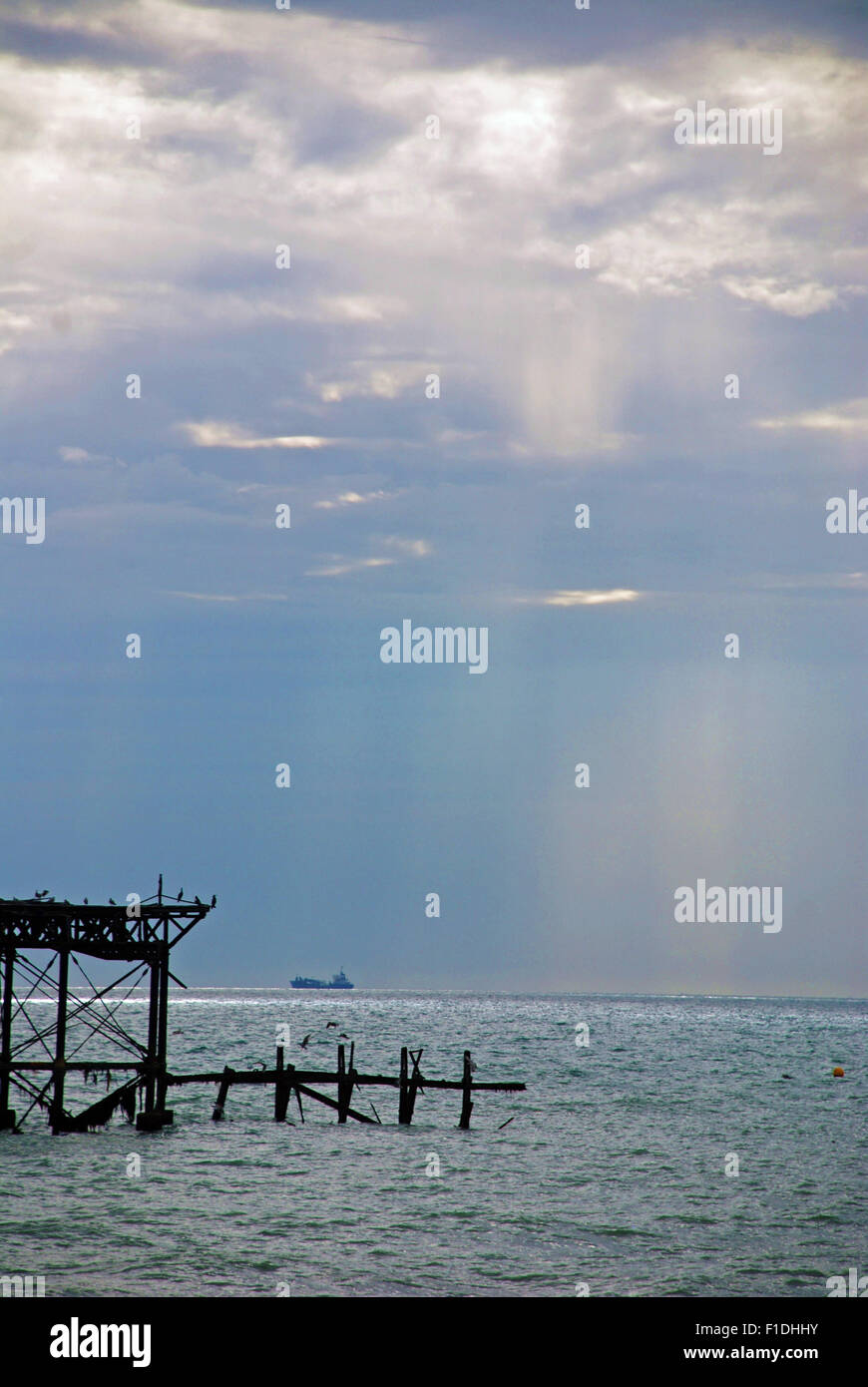 Burnt down remains of West Pier and rays of light on a cloudy sky ...