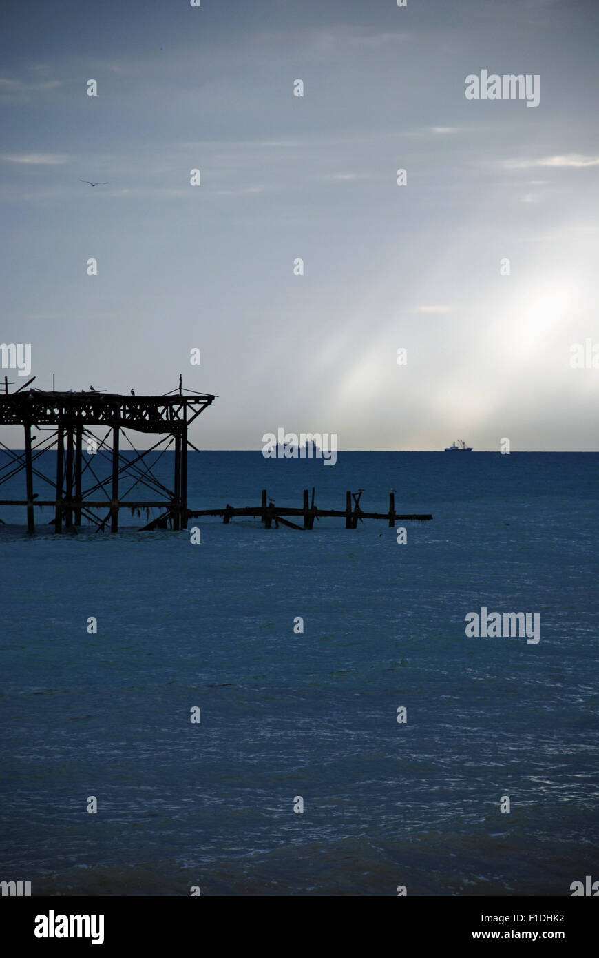Burnt down remains of West Pier and rays of light on a cloudy sky ...