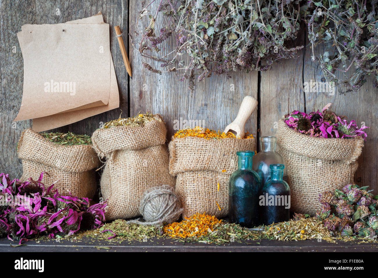 Healing herbs in hessian bags, paper sheet and bottles near wooden wall ...