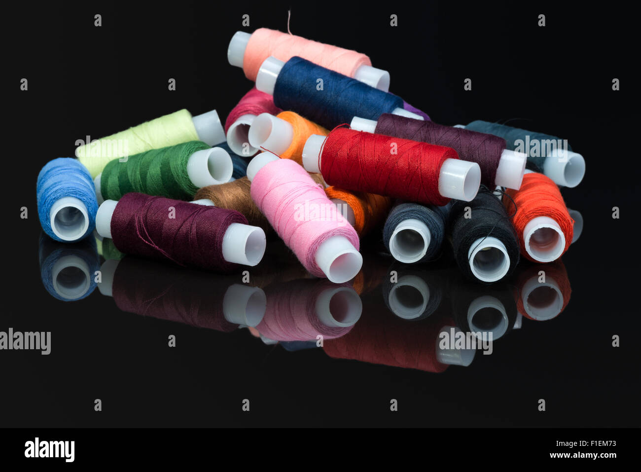 coils with multi-colored sewing threads on a black background Stock ...