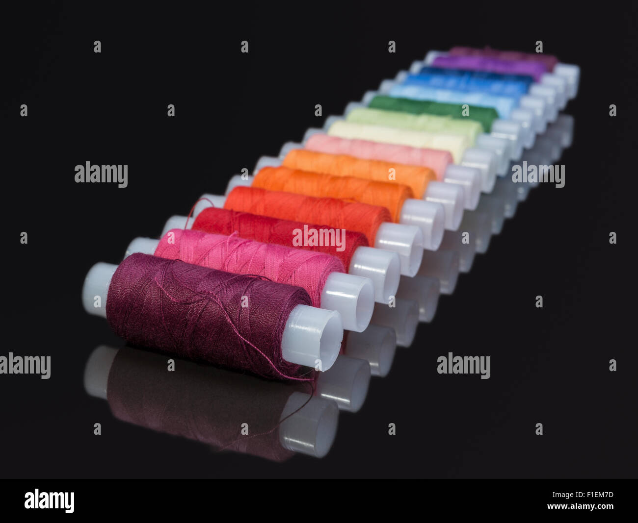 coils with multi-colored sewing threads on a black background Stock ...