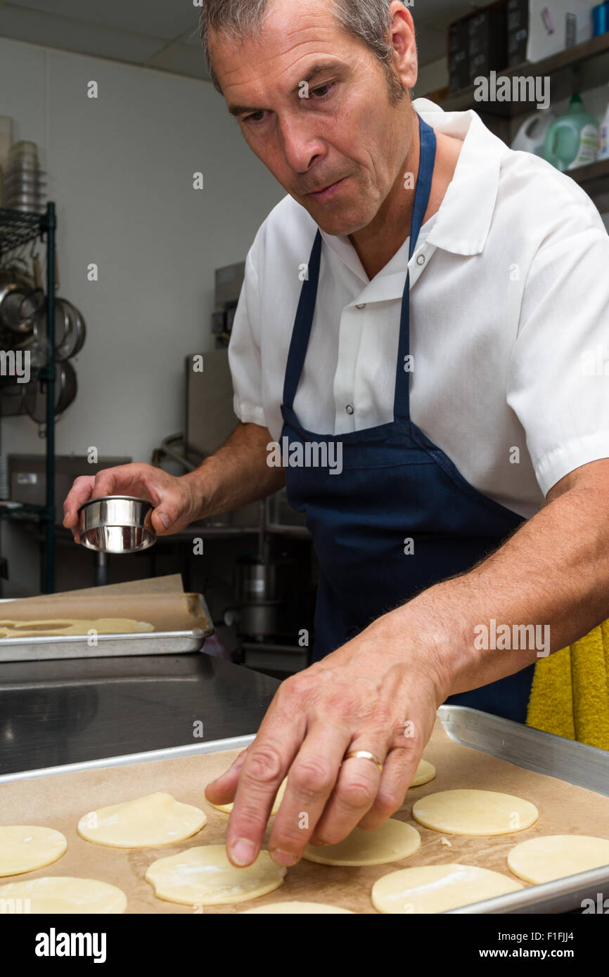 professional chef at work cutting circles of of dough to prepare a ...