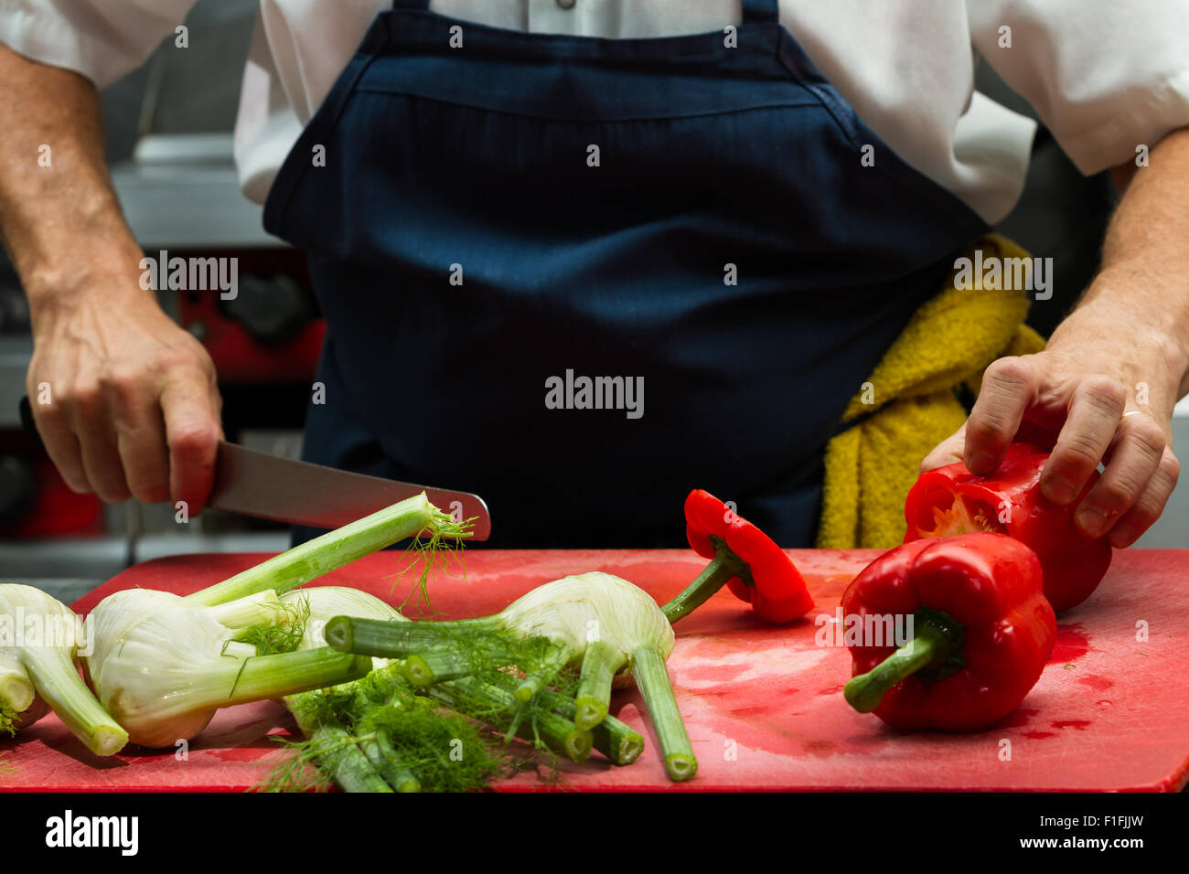close up of a chef's hands slicing fresh vegetables in a restaurant ...