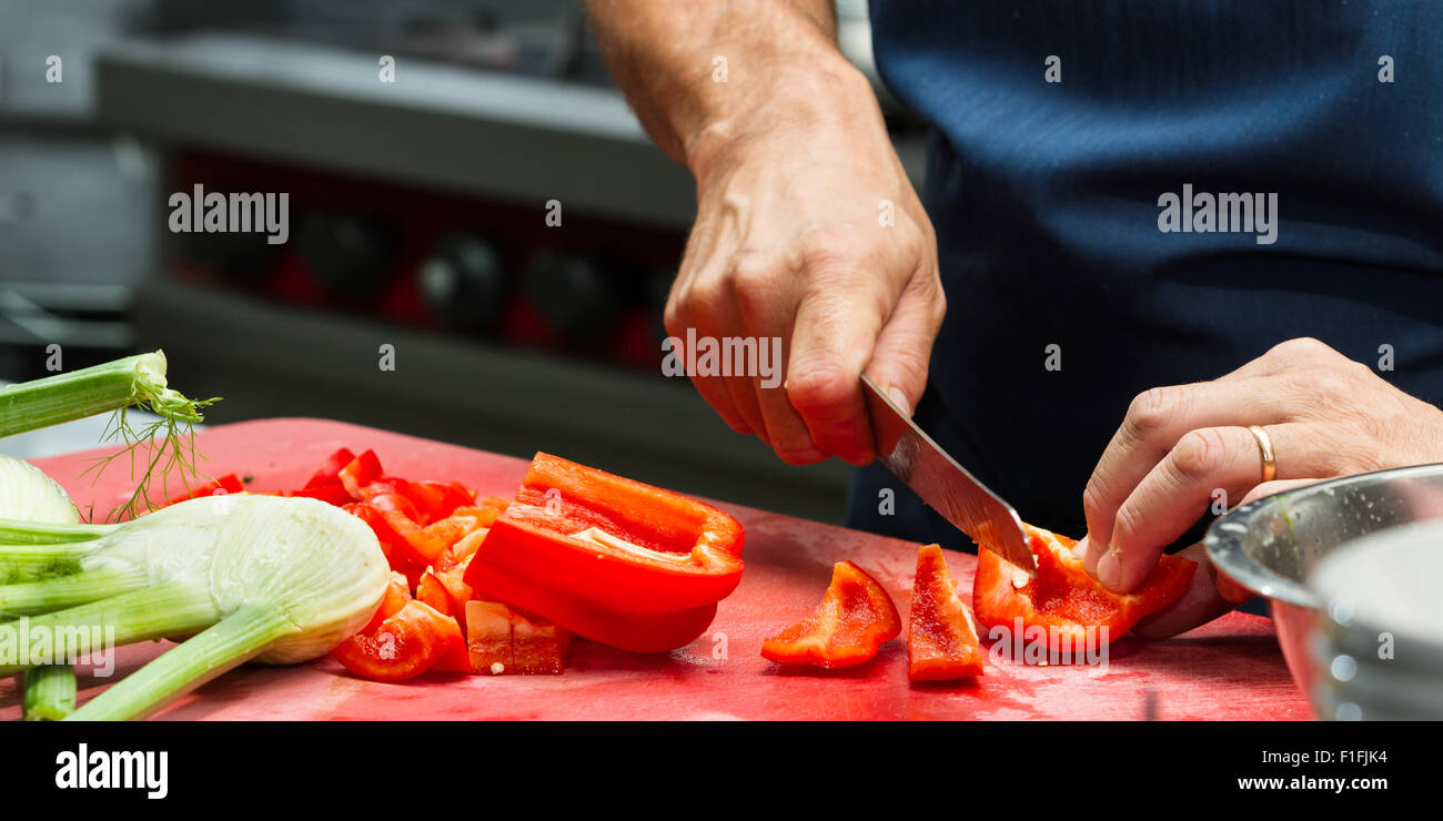 close up of a chef's hands slicing fresh vegetables in a restaurant ...