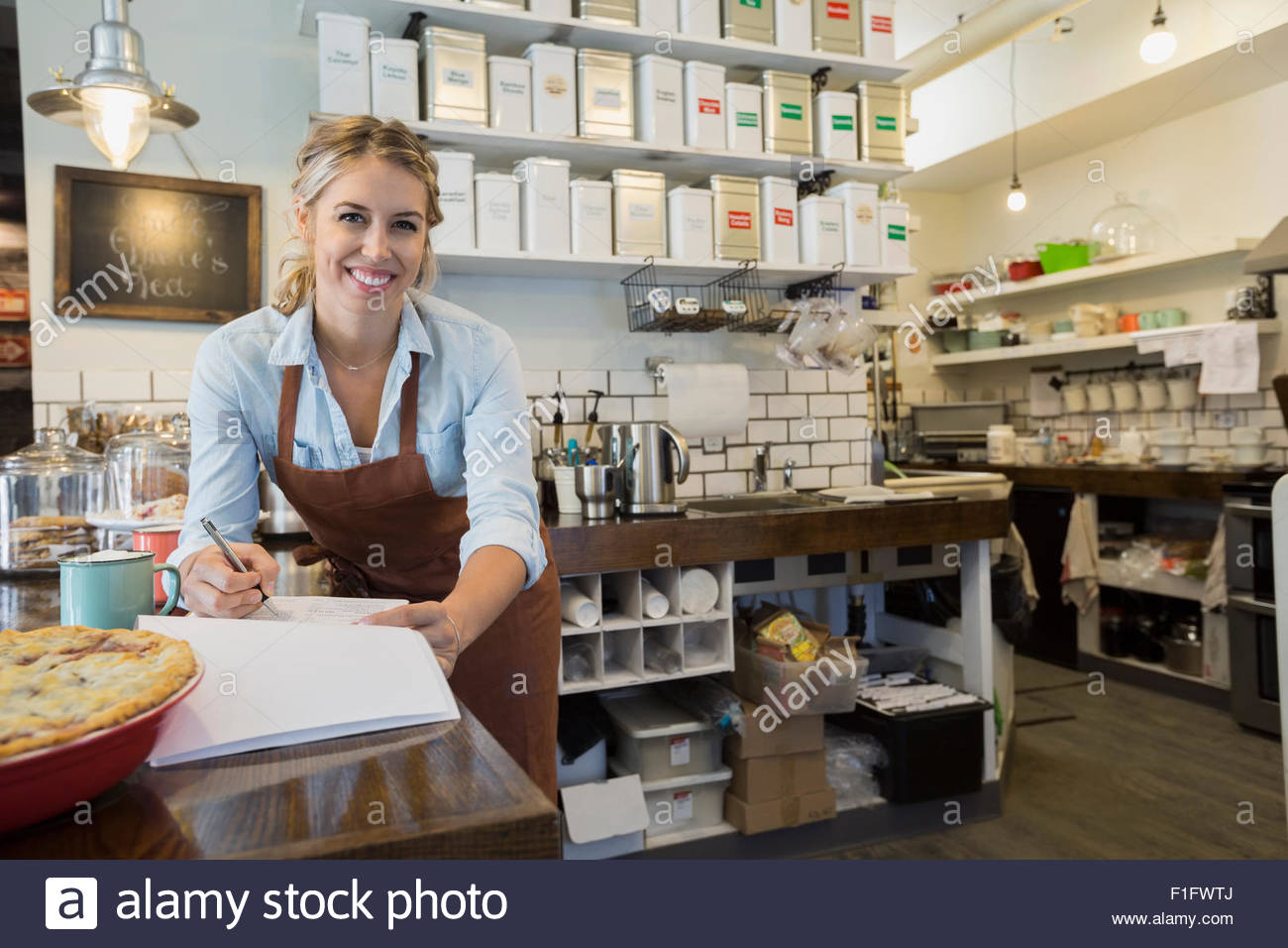 Portrait confident tea shop owner doing paperwork counter Stock Photo ...