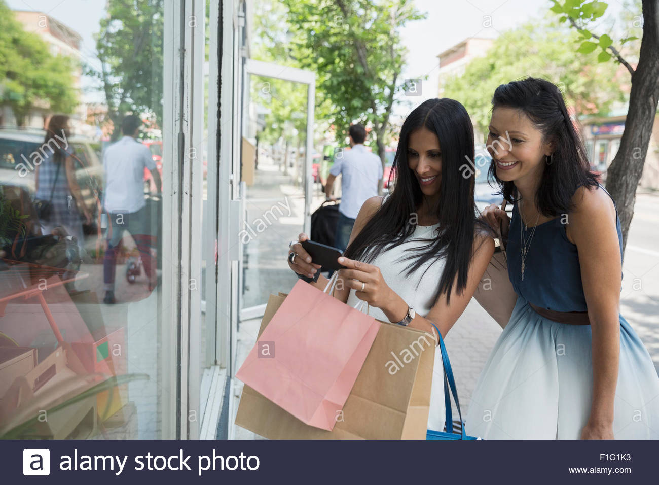 Women photographing window display at storefront Stock Photo - Alamy