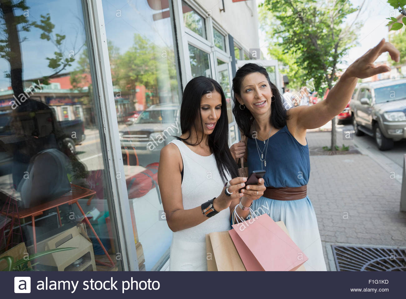 Women with shopping bags and cell phone at storefront Stock Photo - Alamy