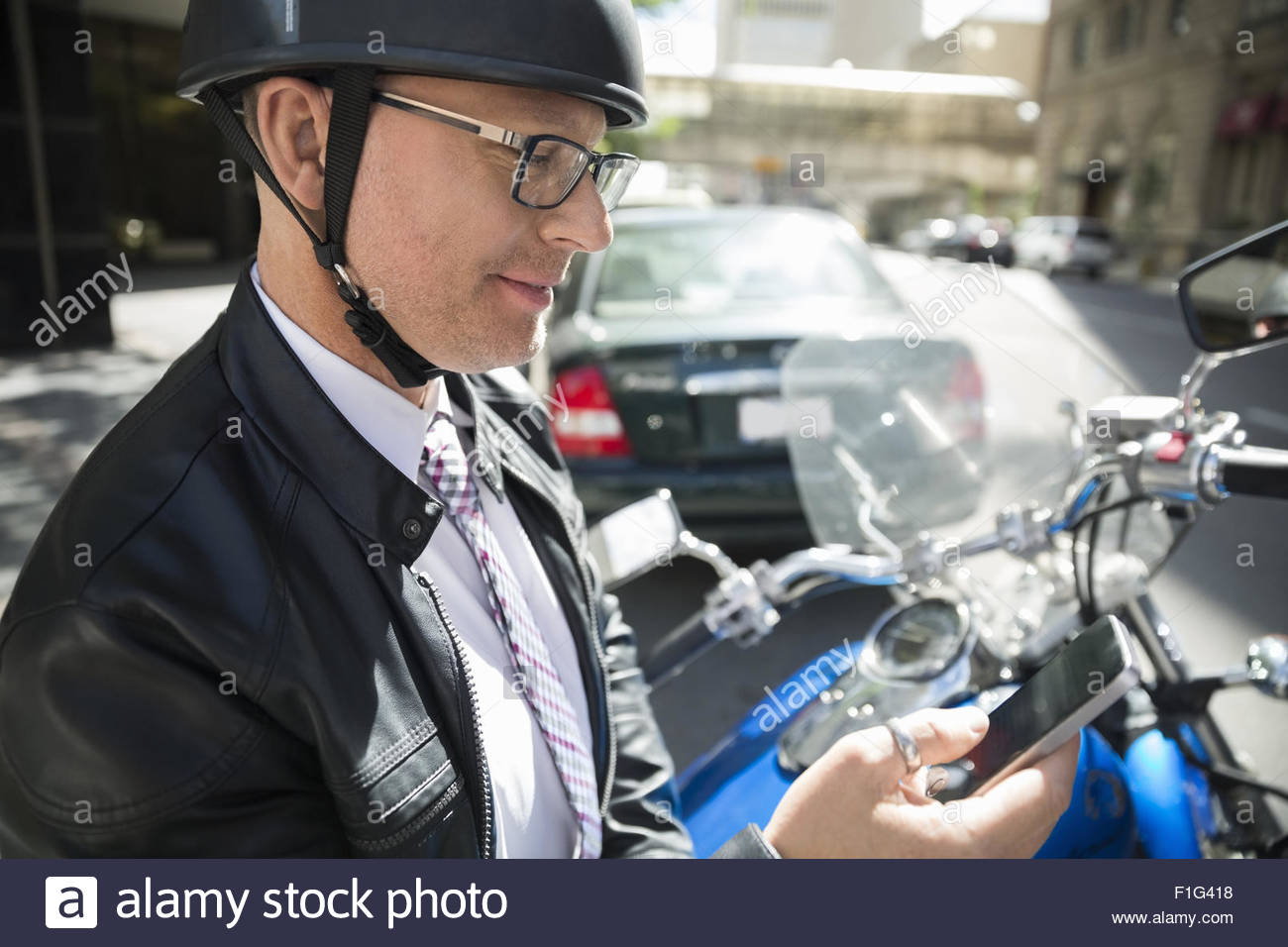 Businessman commuting on motorcycle texting with cell phone Stock Photo ...