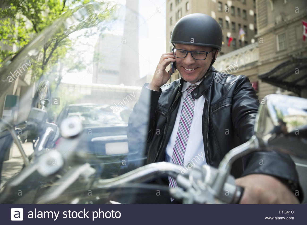Businessman commuting on motorcycle talking cell phone Stock Photo - Alamy