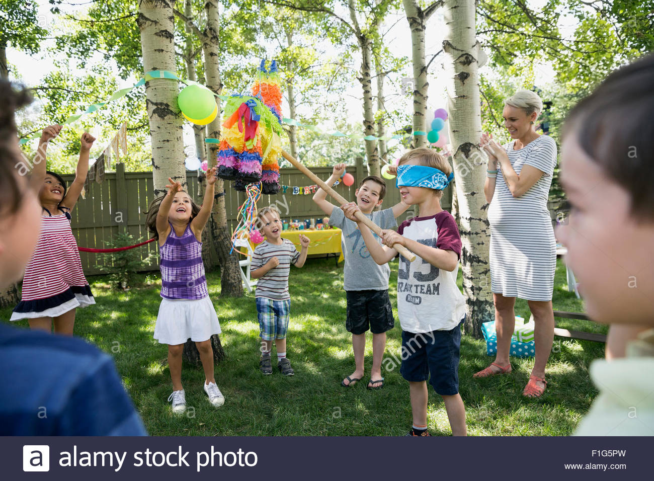 Kids cheering for blindfolded boy swinging at pinata Stock Photo - Alamy