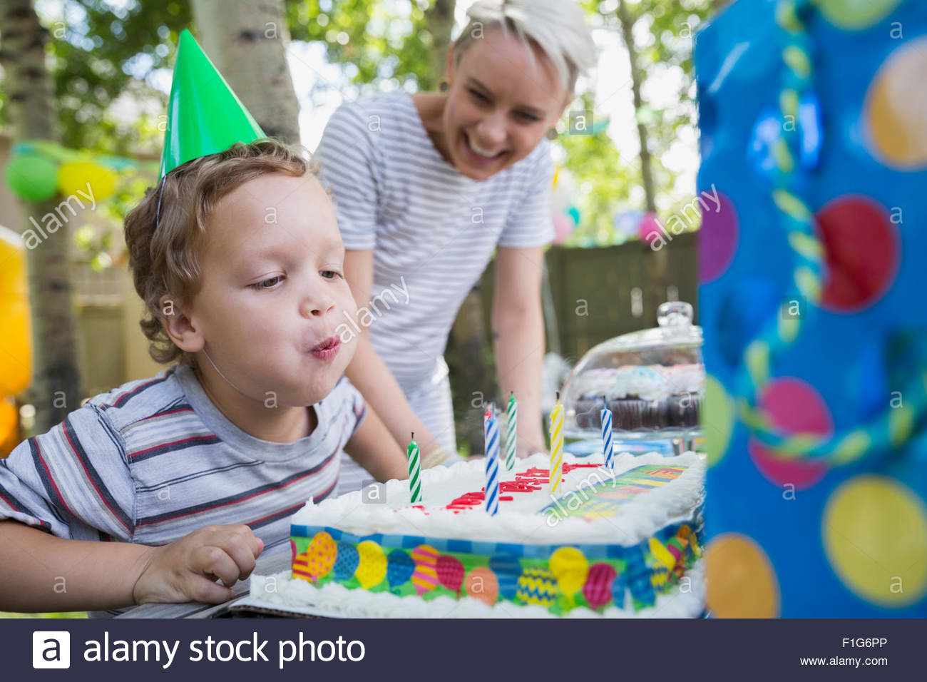 Boy blowing out birthday candles on cake backyard Stock Photo - Alamy