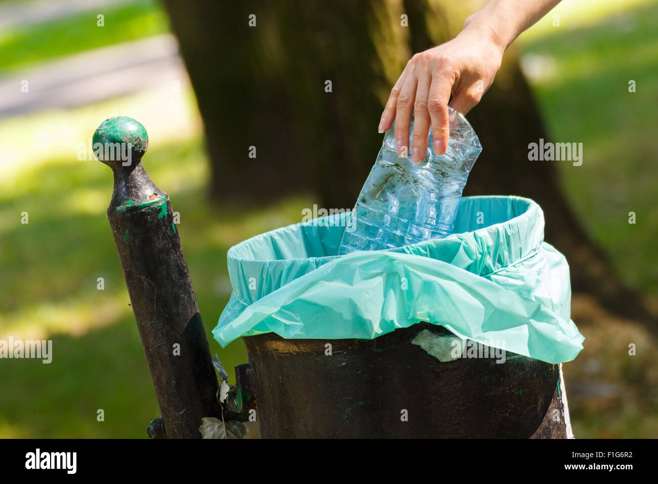 Hand of woman throwing plastic bottle into old trash can, concept of ...