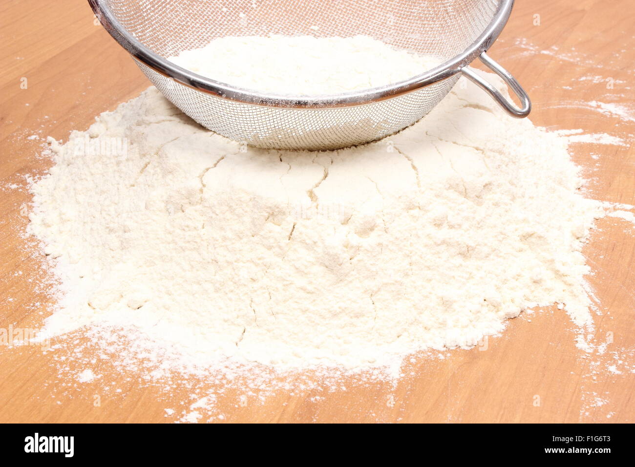 Sifting wheat flour through sieve, heap of wheat flour lying on wooden ...