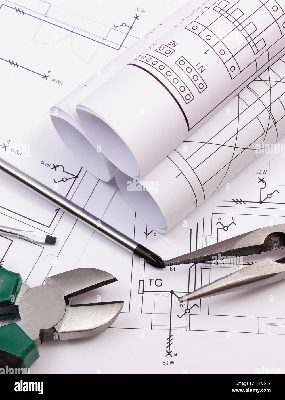 Rolls of diagrams, metal pliers and screwdriver on electrical ...