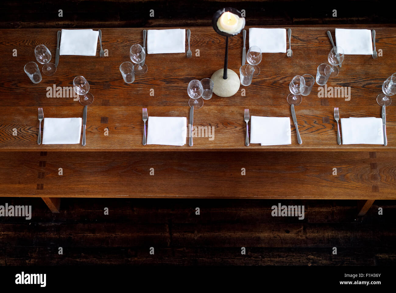 A aerial view of an old wooden table laid out with glasses, napkins ...