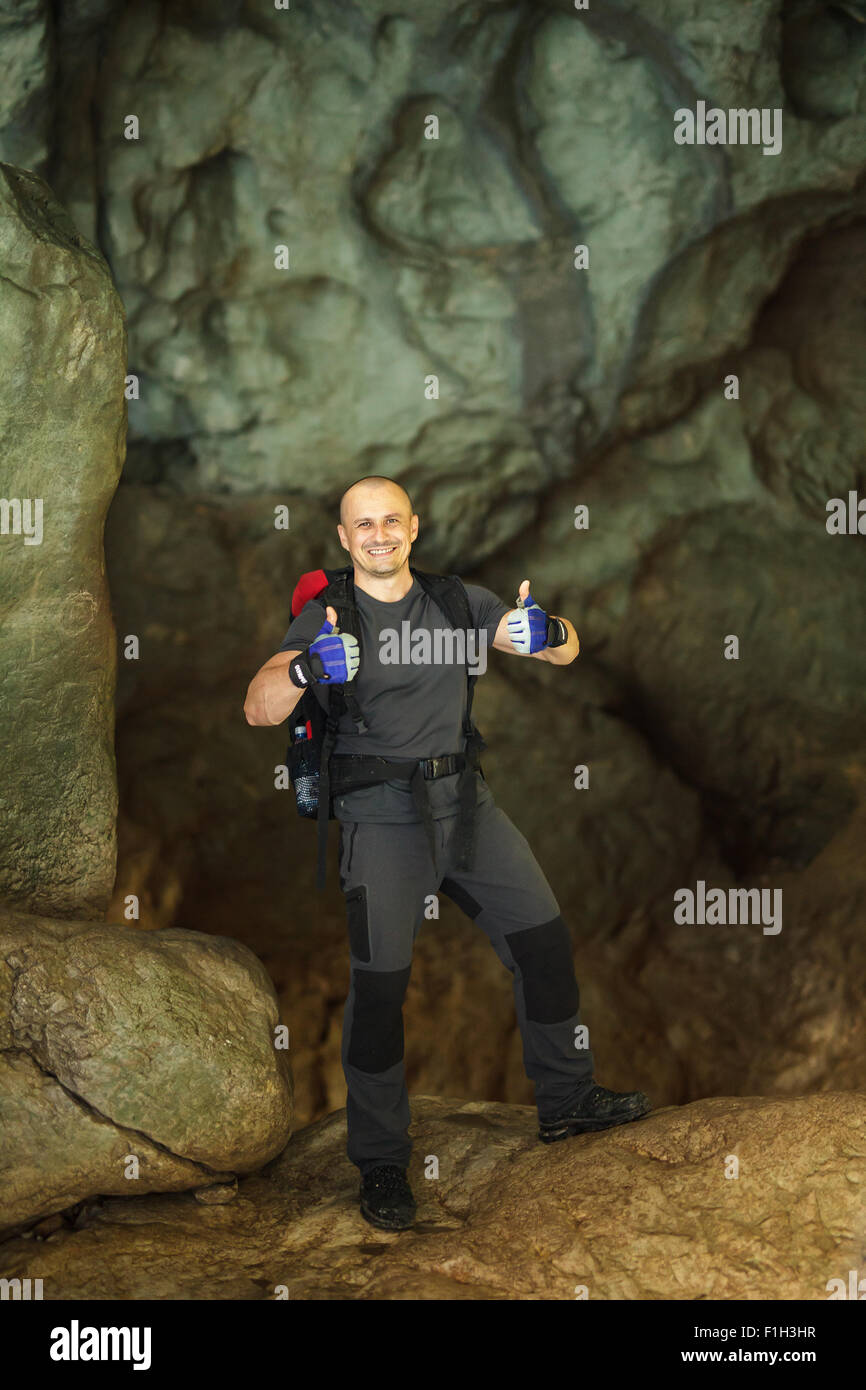 Happy man with thumbs up standing inside a large cave Stock Photo - Alamy