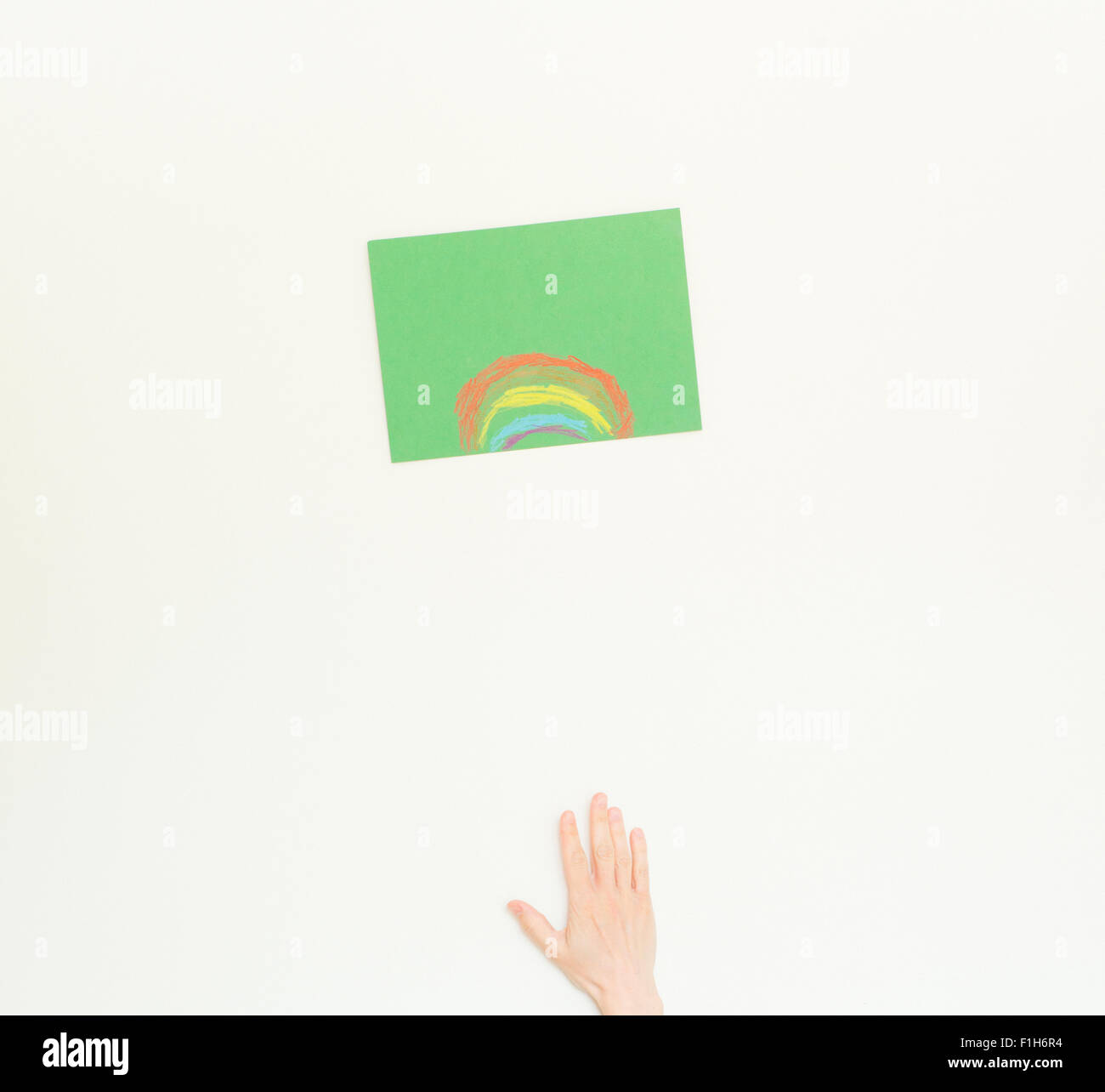 Adult hand reaching for child drawing of a rainbow. Symbolic and ...