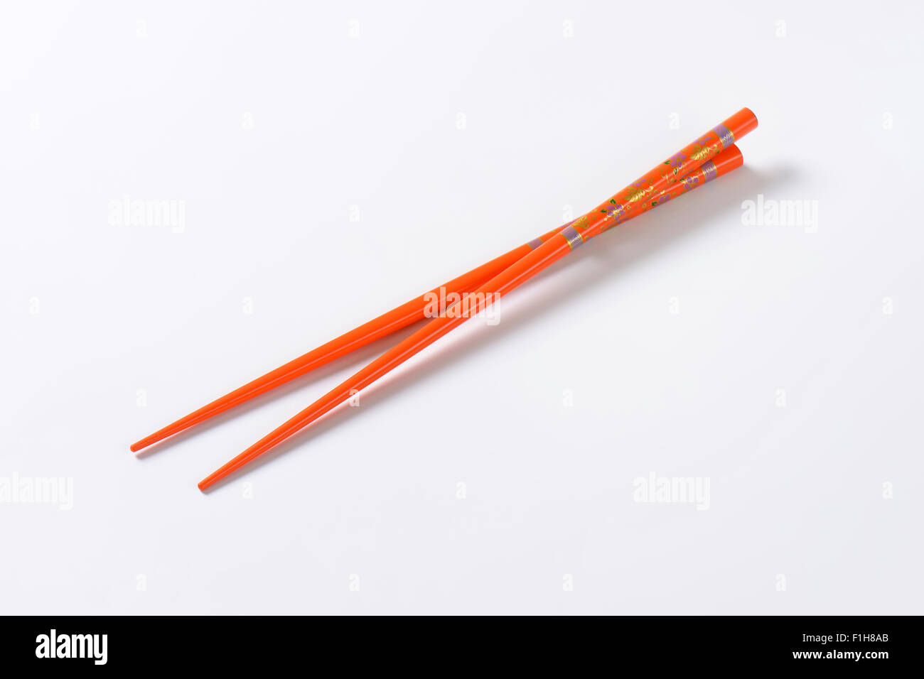 pair of orange chopsticks on white background Stock Photo - Alamy