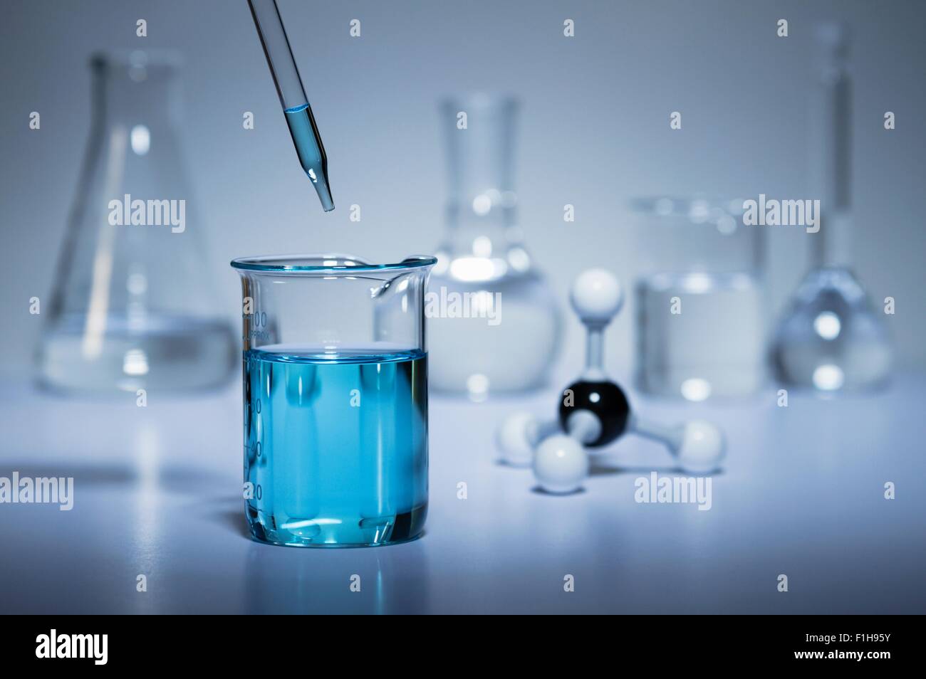 Chemistry research. A pipette transferring liquid to a beaker and a ...