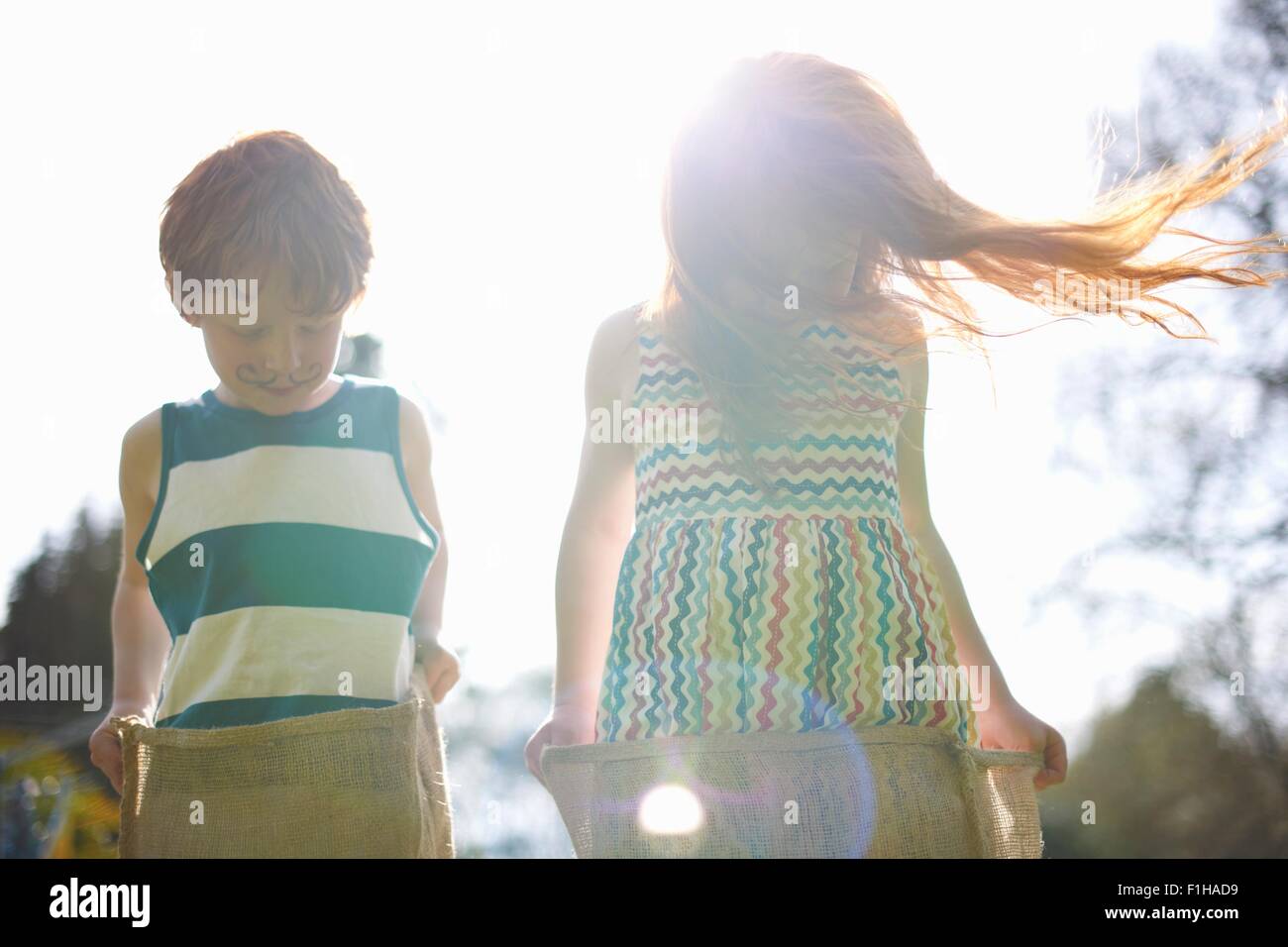 Two young children having sack race Stock Photo - Alamy