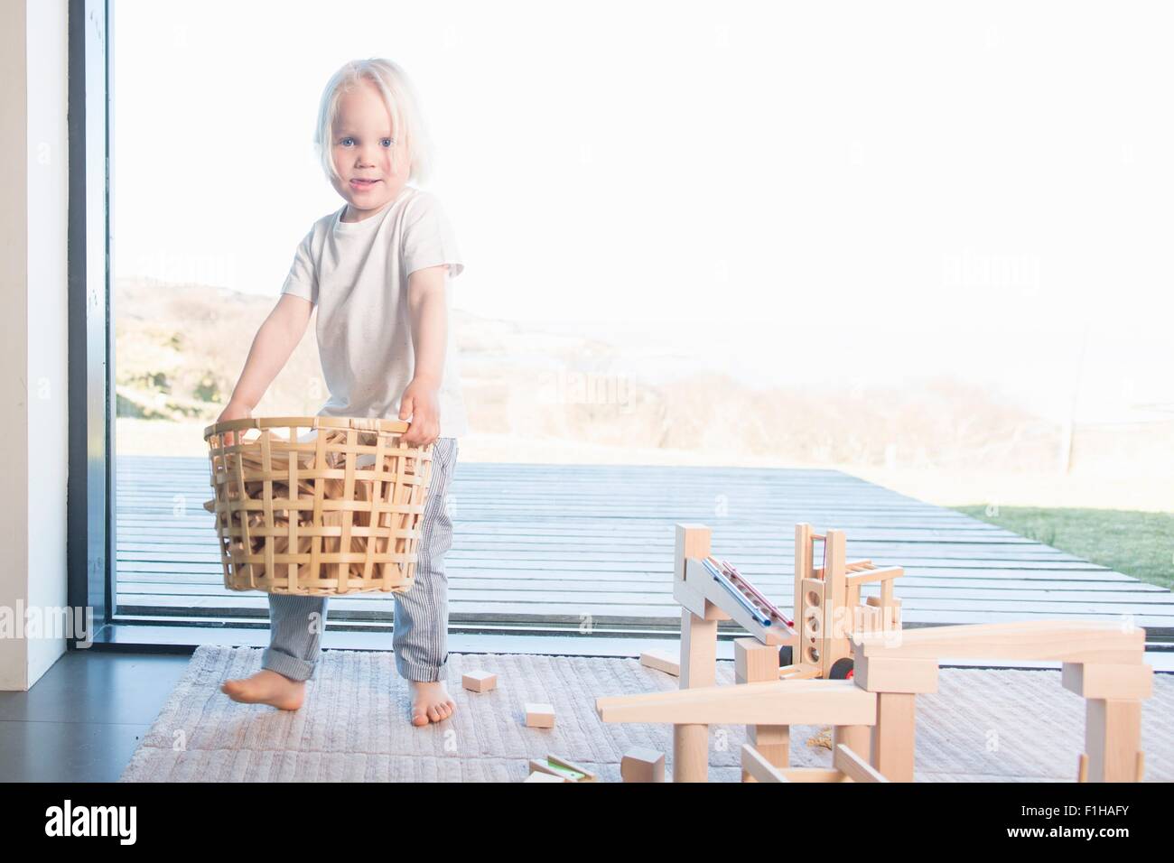 Boy carrying basket of wooden blocks Stock Photo - Alamy
