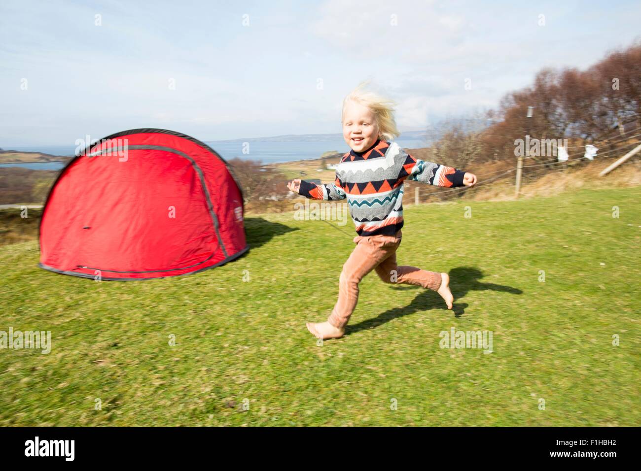 Boy running on grass with tent Stock Photo - Alamy