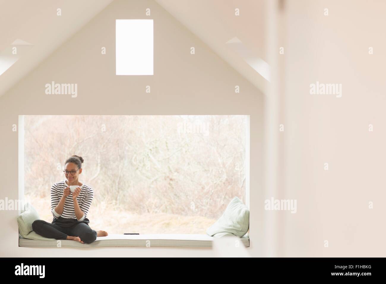 Mid adult woman sitting in window seat Stock Photo - Alamy