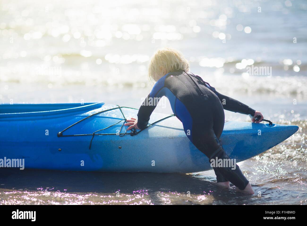Boy in water pushing canoe Stock Photo - Alamy