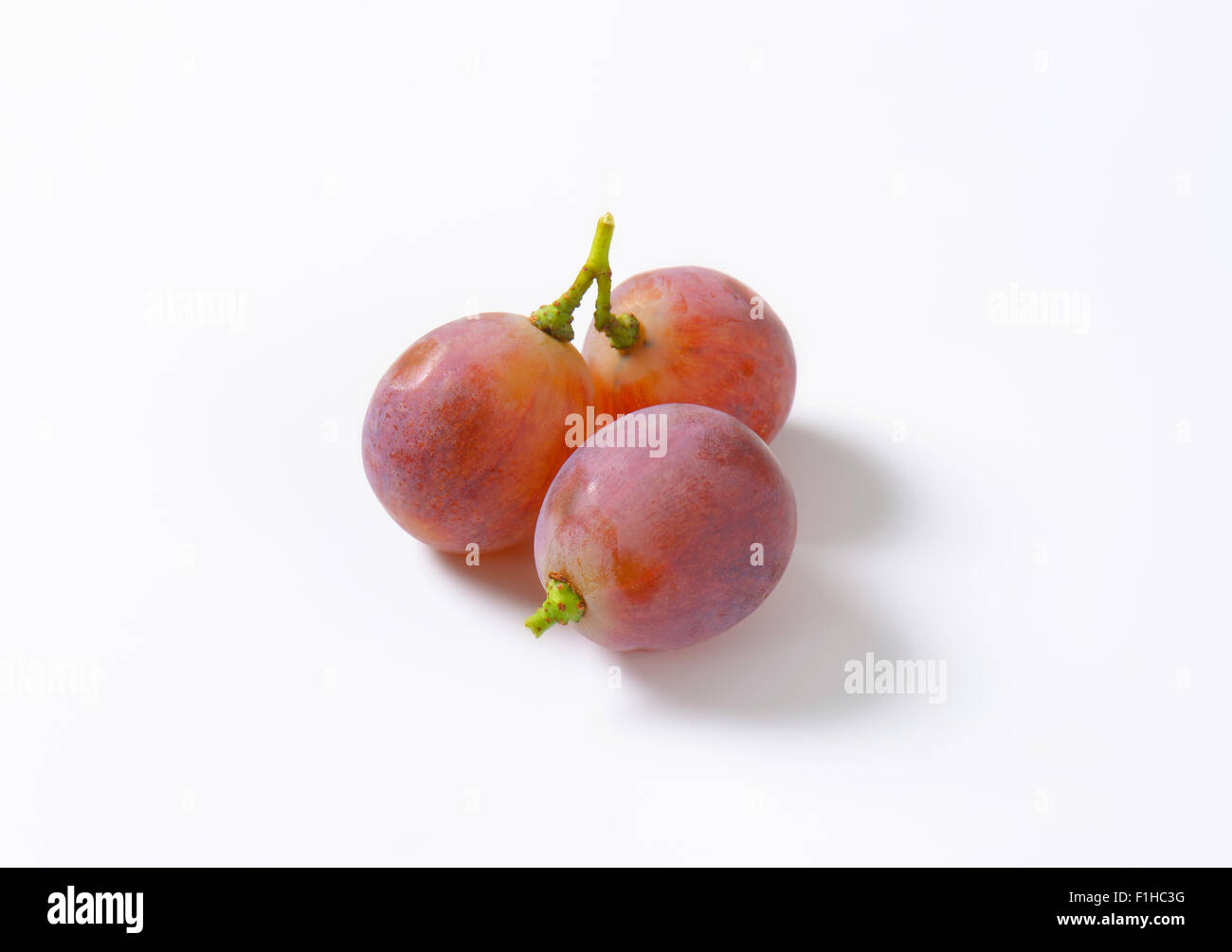 three red grapes on white background Stock Photo - Alamy