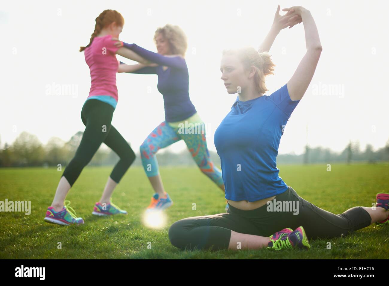 Three women exercising and stretching in the park Stock Photo - Alamy