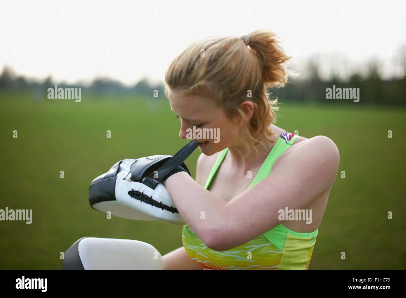 Portrait of a woman putting on boxing pads in the park Stock Photo - Alamy