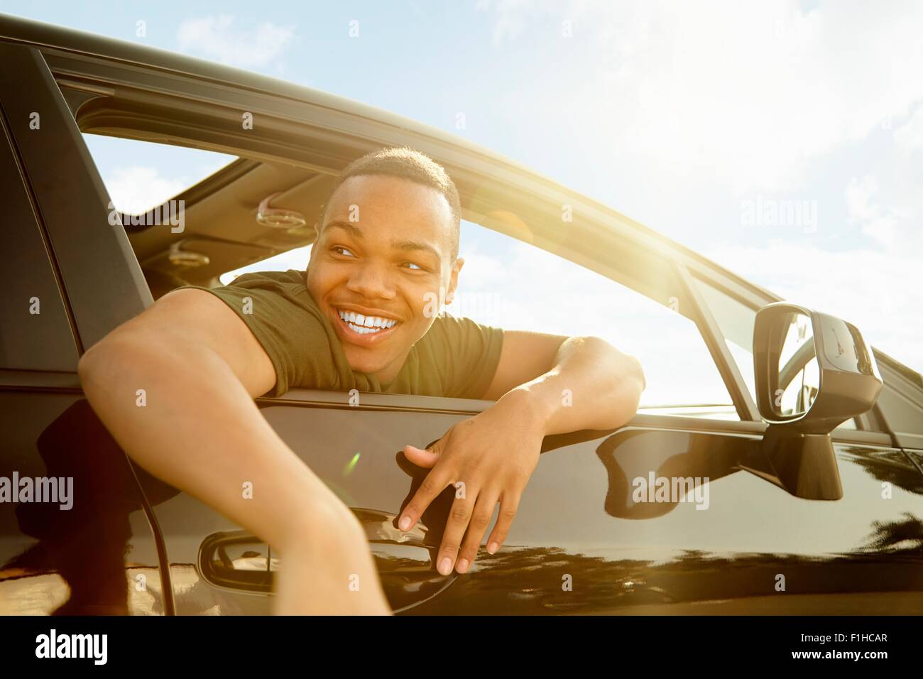 Young man leaning out of car window smiling Stock Photo - Alamy