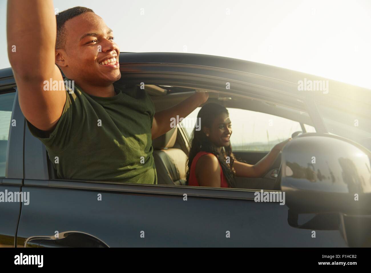 Young man leaning out of car window smiling, arms raised Stock Photo ...
