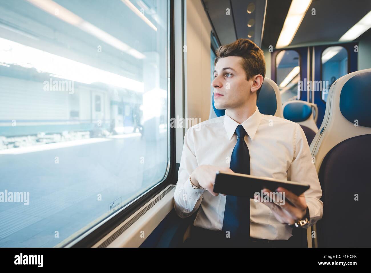 Portrait of young businessman commuter using digital tablet on train ...