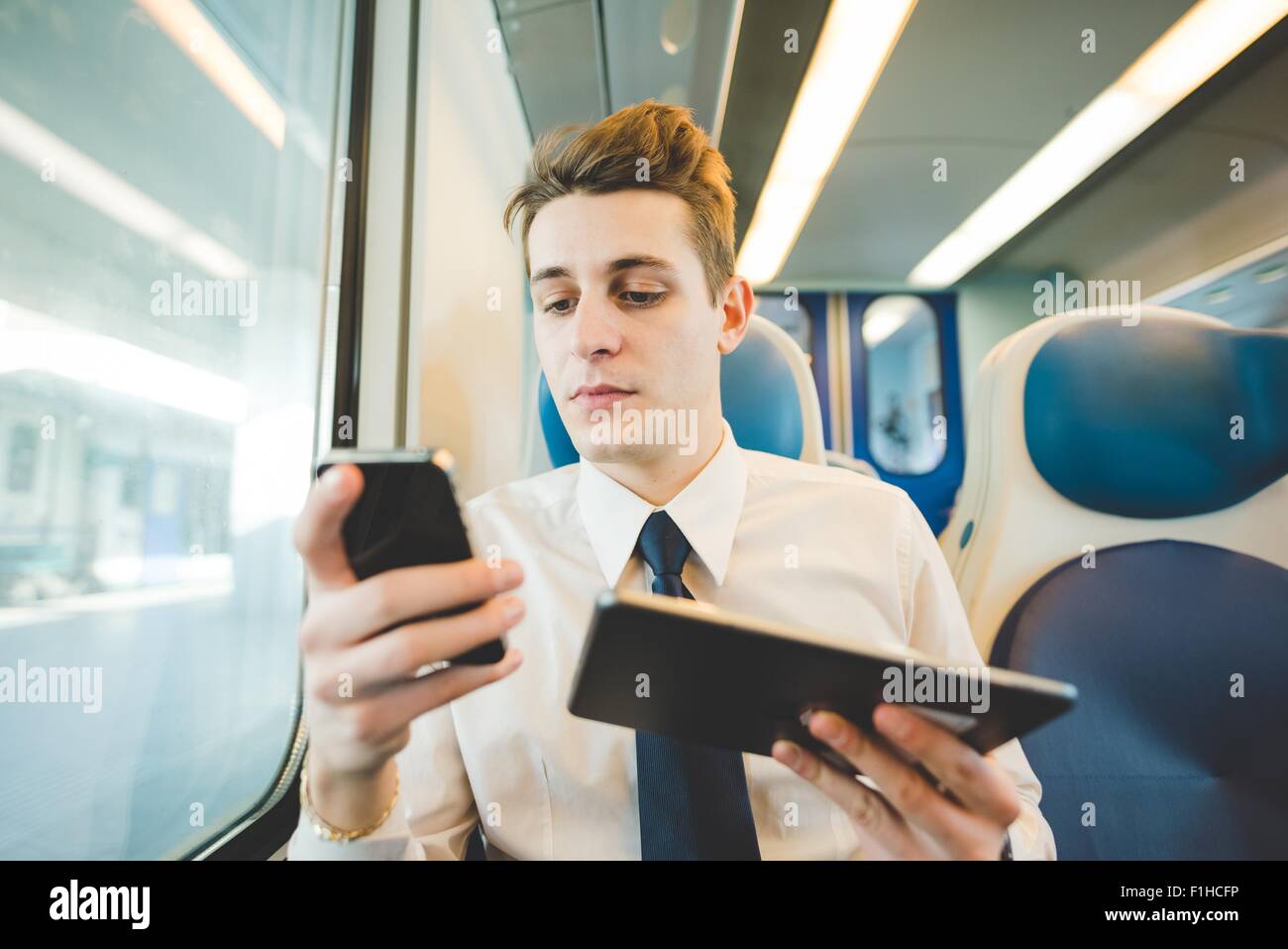 Portrait of young businessman commuter using digital tablet on train ...