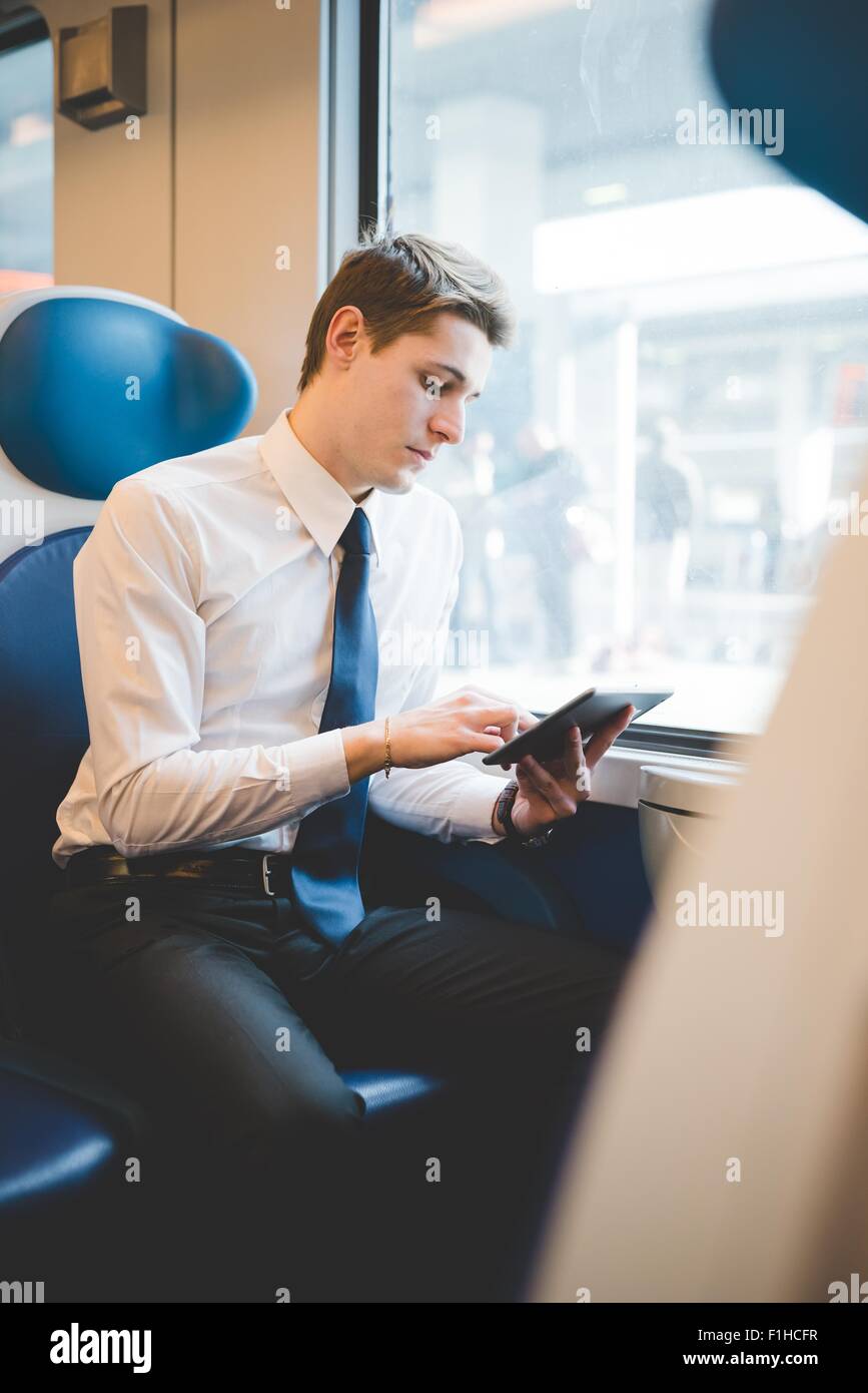 Portrait of young businessman commuter using digital tablet on train ...