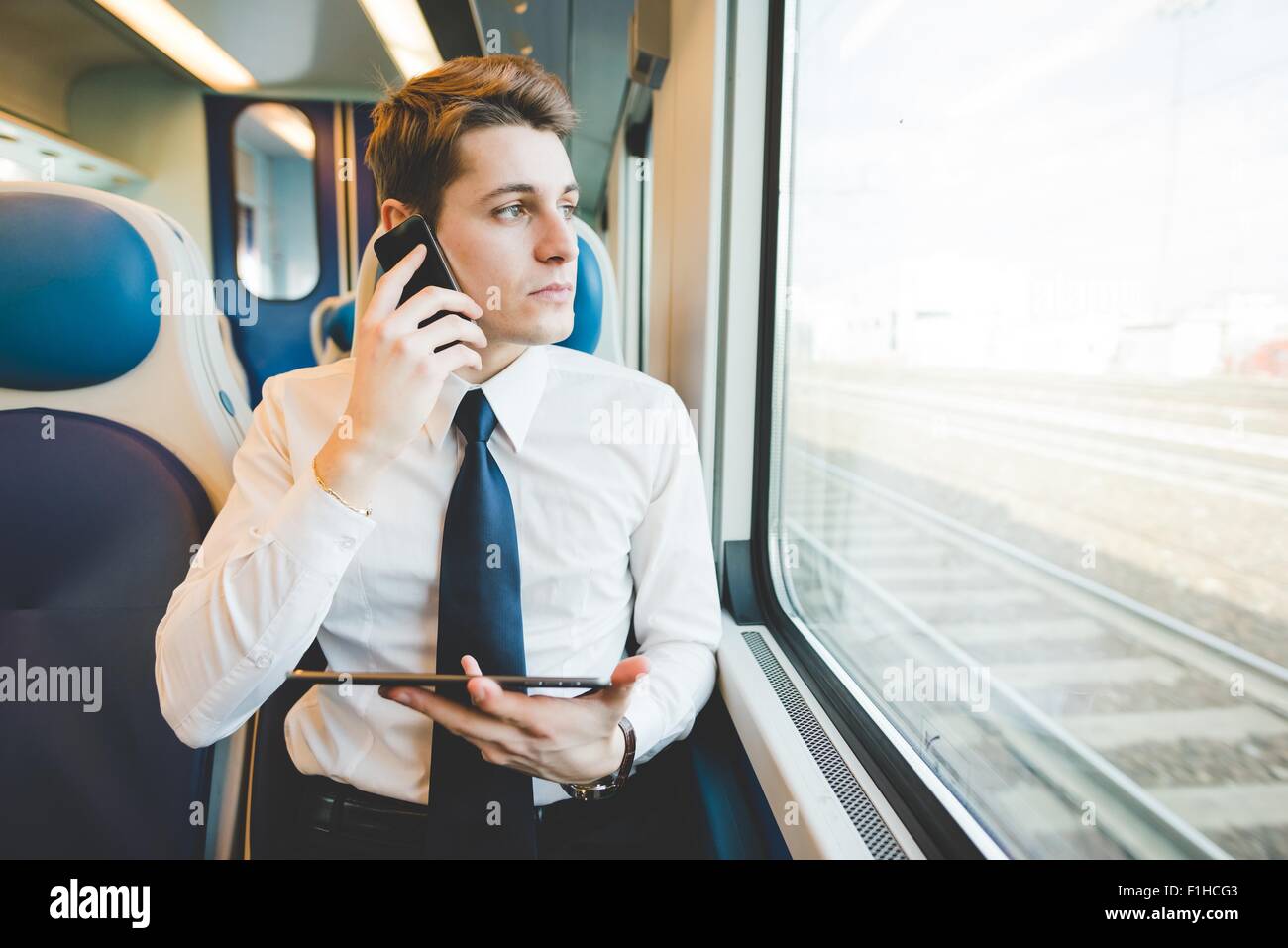 Portrait of young businessman commuter using digital tablet on train ...