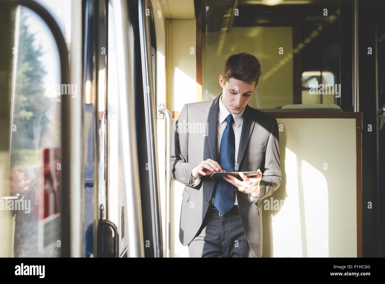 Portrait of young businessman commuter using digital tablet on train ...