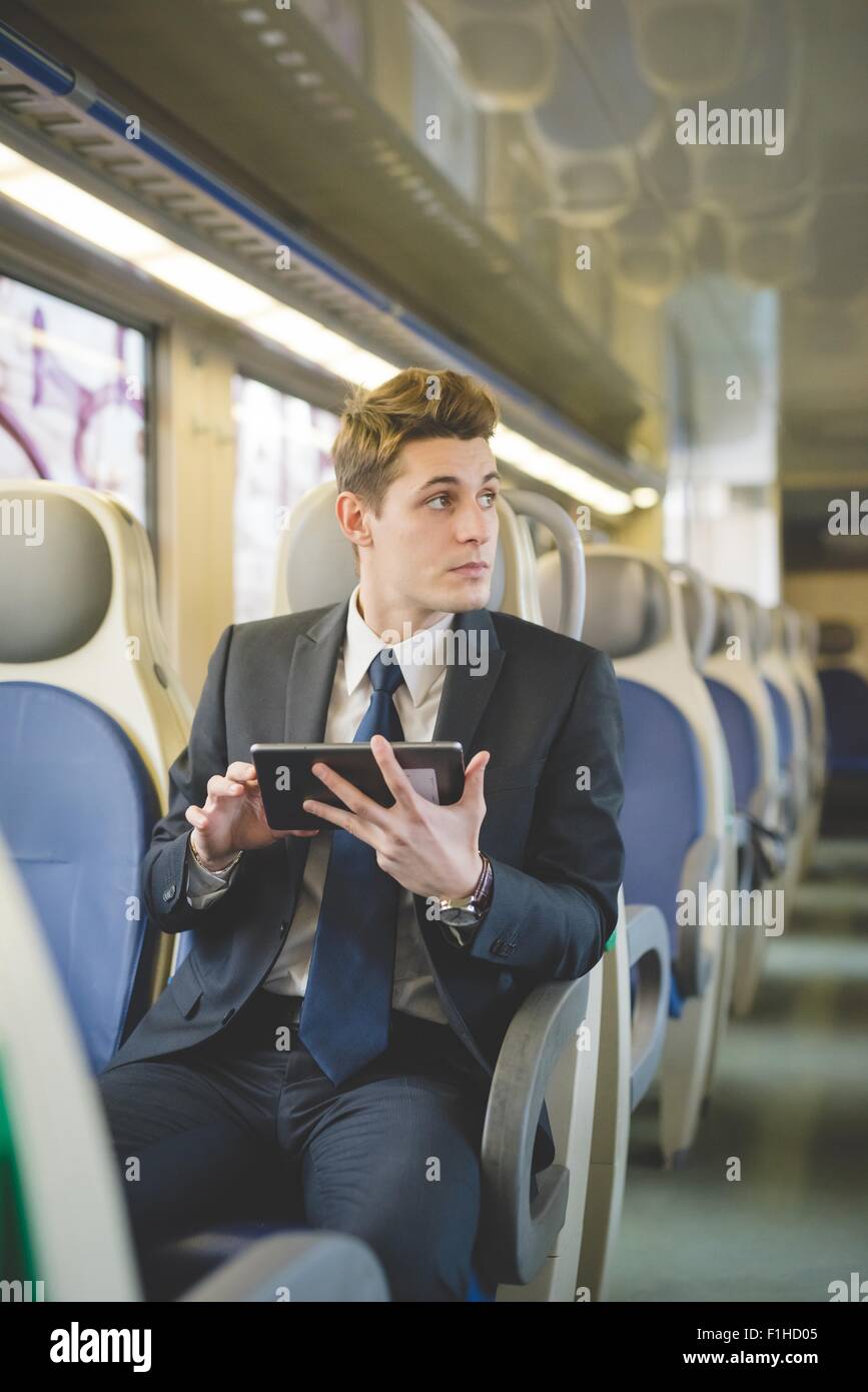 Portrait of young businessman commuter using digital tablet on train ...