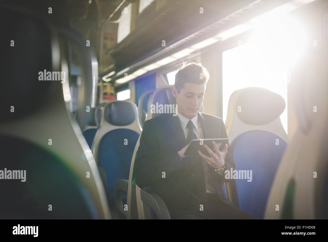 Portrait of young businessman commuter using digital tablet on train ...