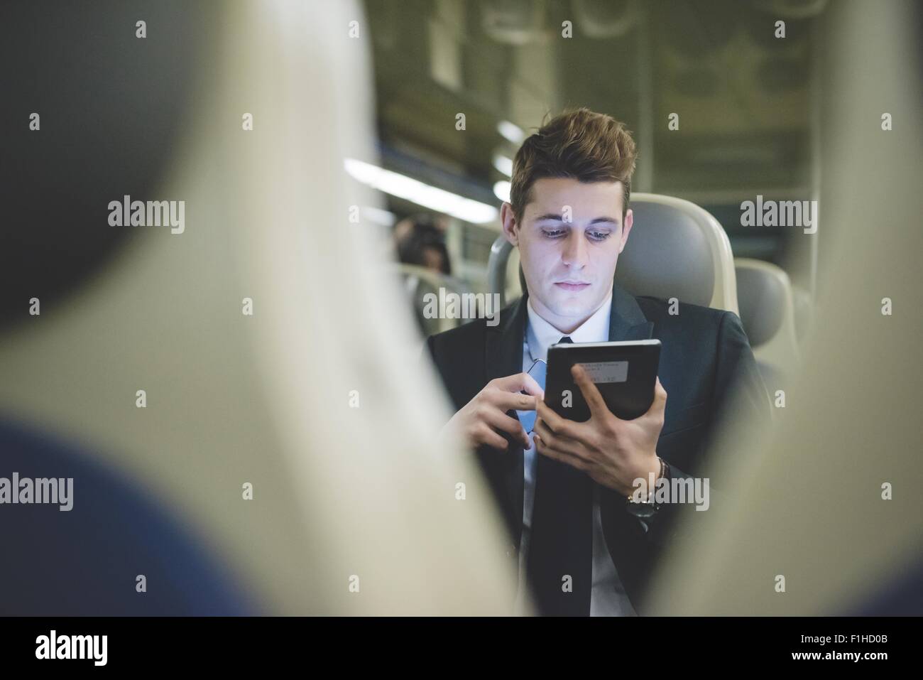 Portrait of young businessman commuter using digital tablet on train ...