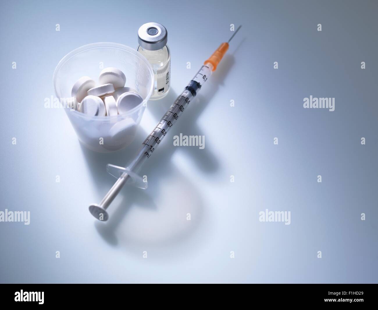 White tablets in plastic measuring cup with syringe and drug vial Stock ...