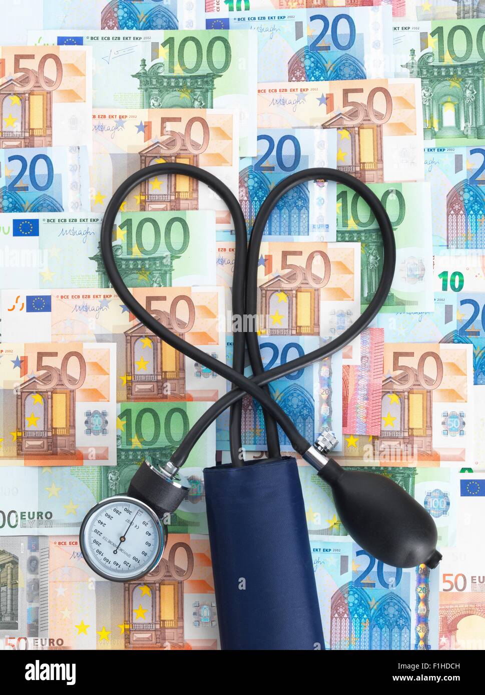 Blood pressure gauge on top of euro currency notes, tubes twisted into ...