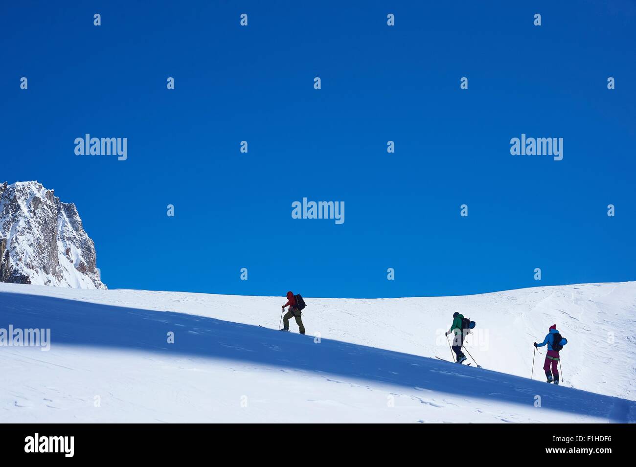 Silhouetted view of three skiers moving up Mont Blanc massif, Graian ...