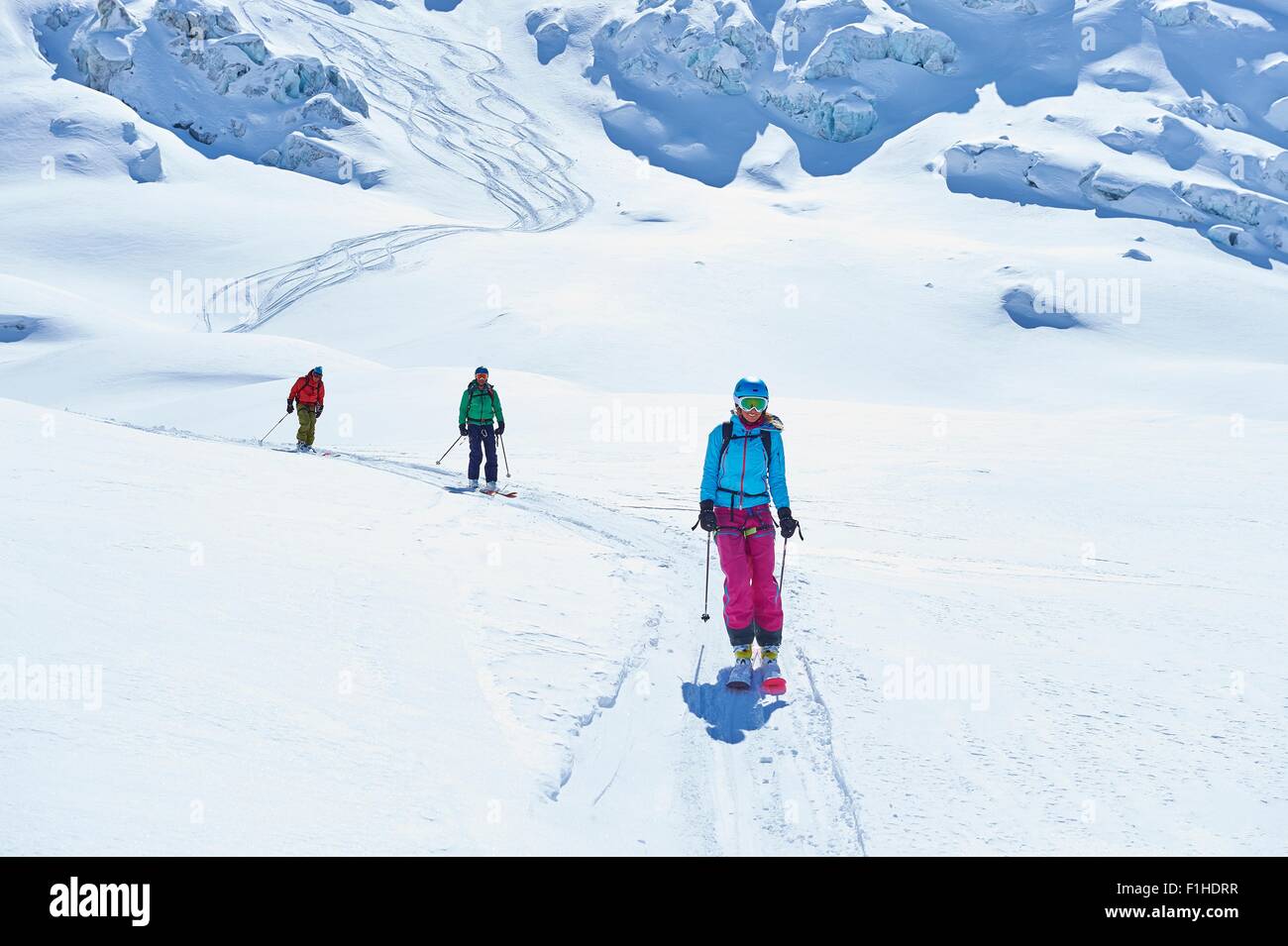 Row of three adult skiers skiing down Mont Blanc massif, Graian Alps ...