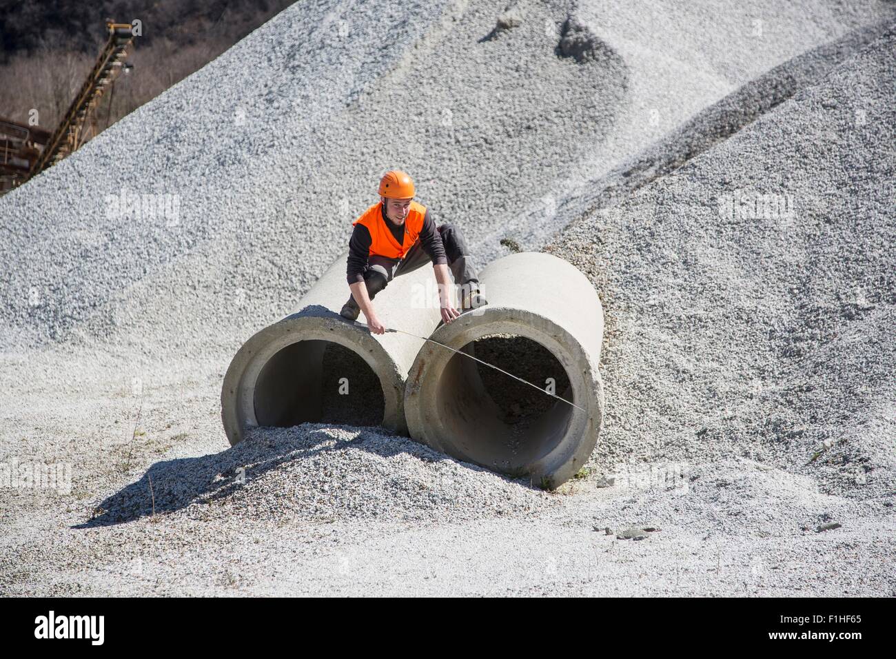 Quarry worker measuring industrial pipes at quarry Stock Photo - Alamy