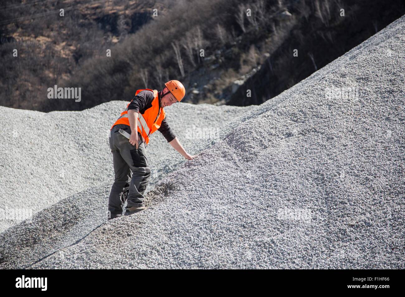 Quarry worker measuring on gravel mound at quarry Stock Photo - Alamy