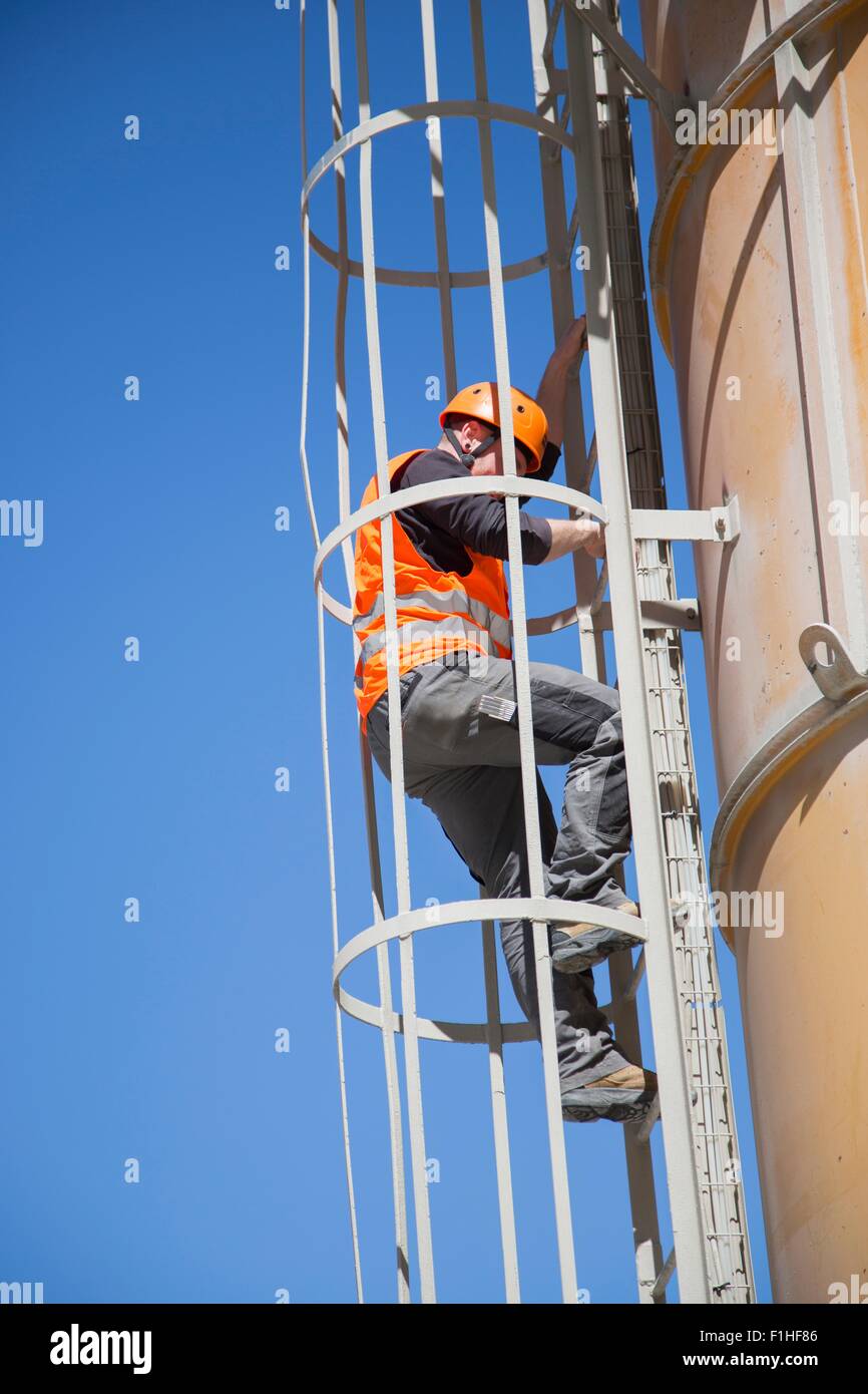 Worker climbing smoke stack ladder Stock Photo - Alamy
