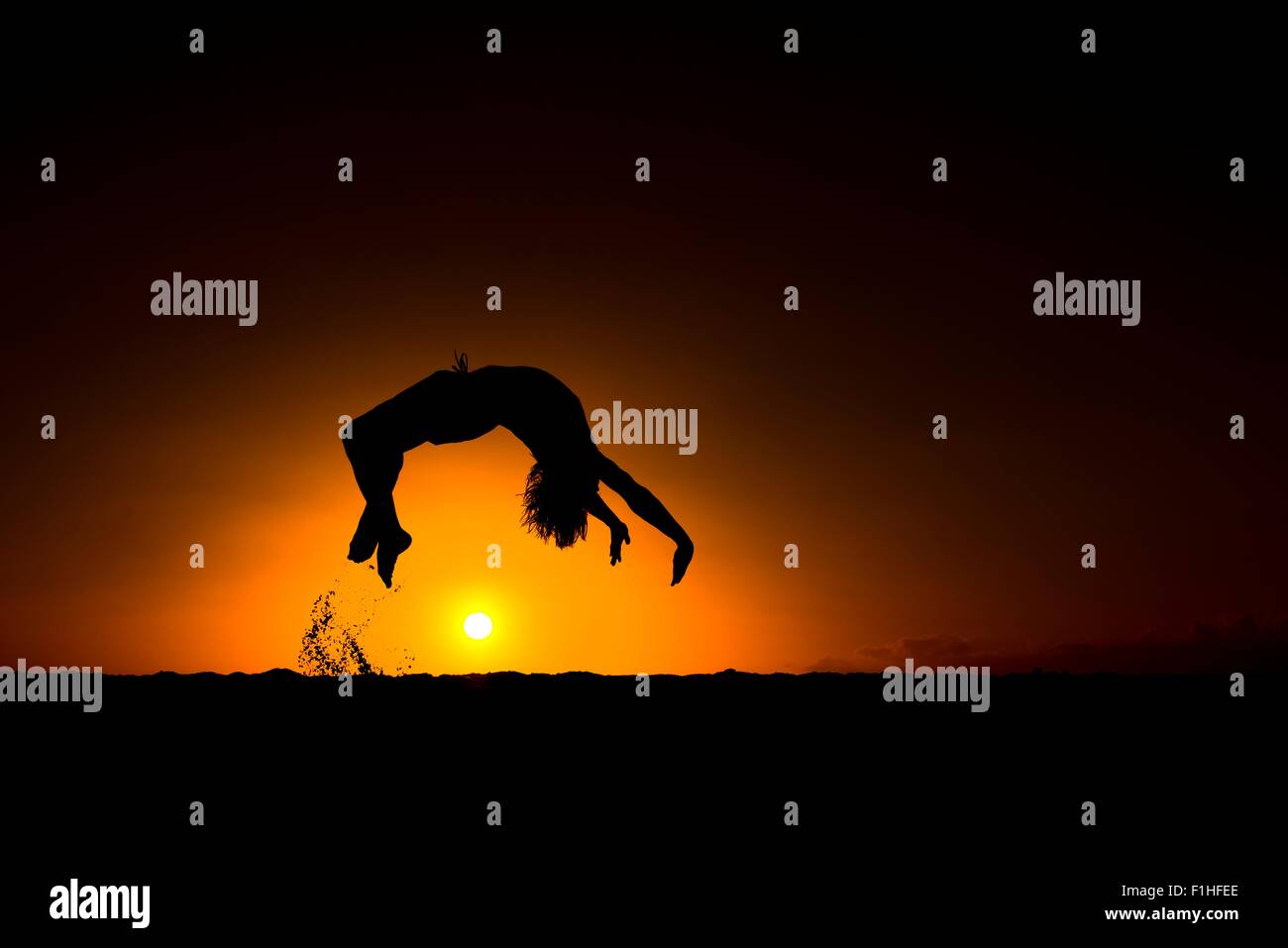Silhouette of man doing back flip, at sunset, Omakaha, Oahu, Hawaii ...